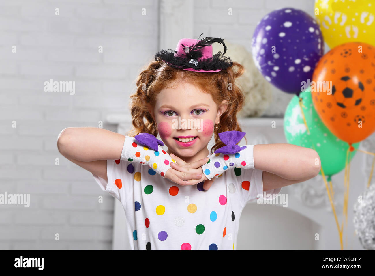 red-haired girl in the image of a clown . In a white room with balloons ...