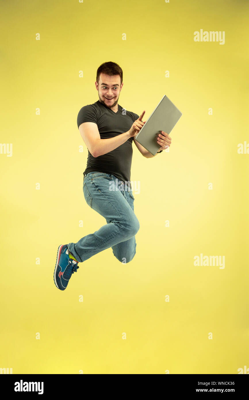 Full length portrait of happy jumping man with gadgets isolated on ...