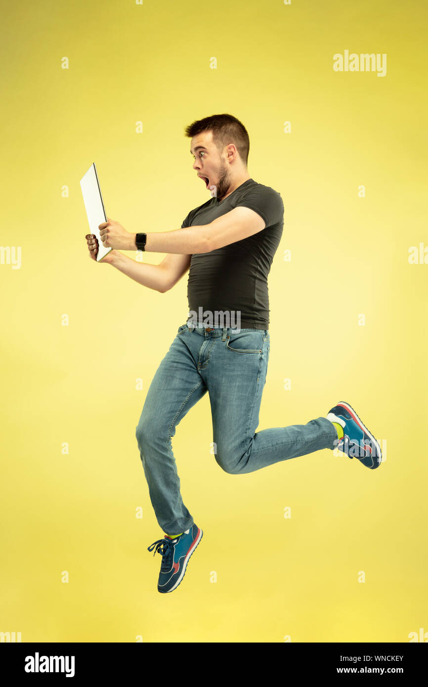 Full length portrait of happy jumping man with gadgets isolated on ...