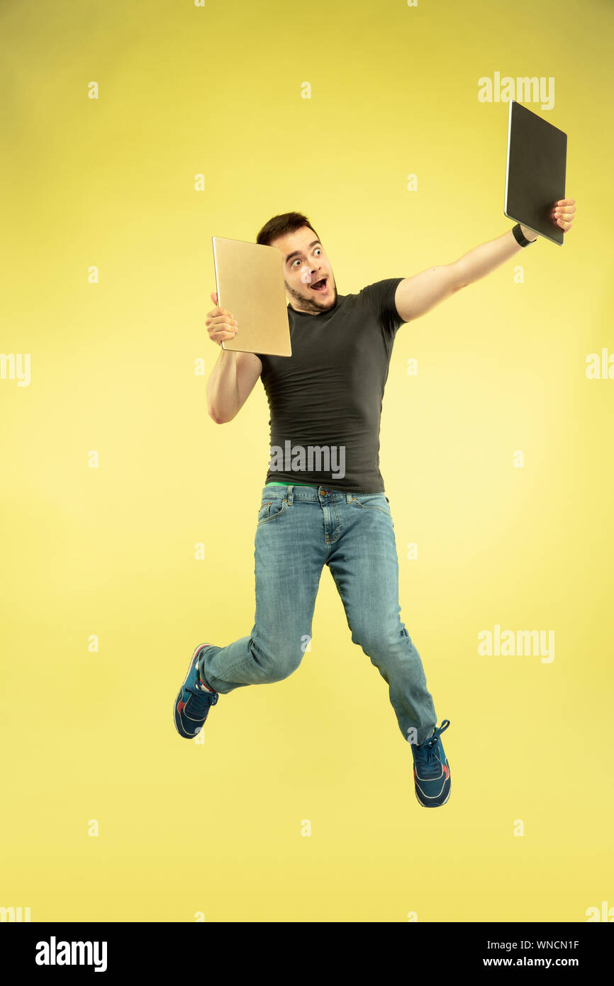 Weightless. Full length portrait of happy jumping man with gadgets ...