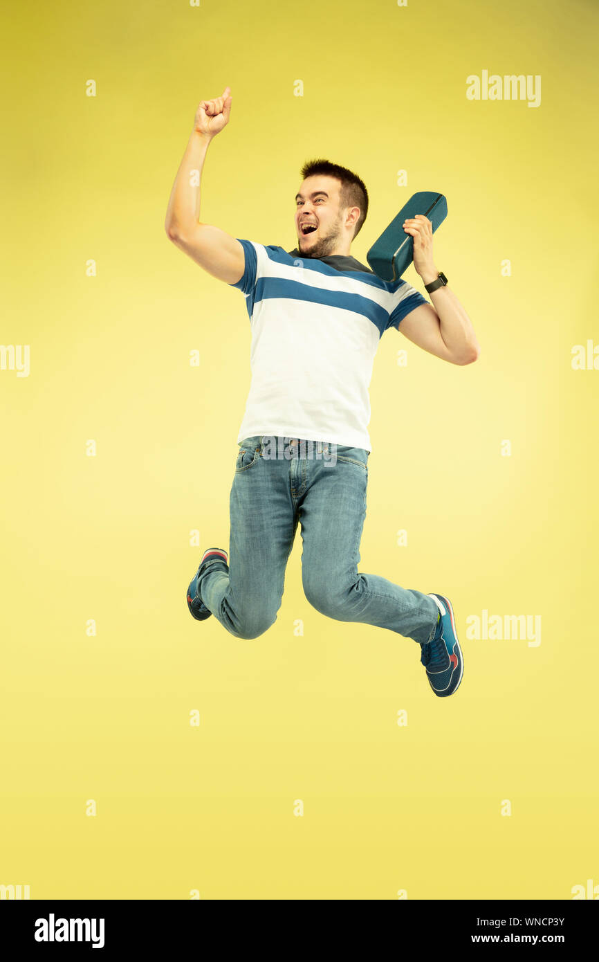 Sky sound. Full length portrait of happy jumping man with gadgets on ...