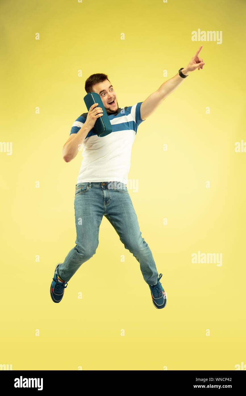 Sky sound. Full length portrait of happy jumping man with gadgets on ...