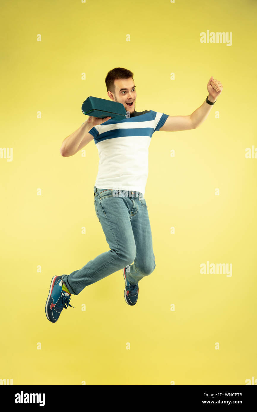 Sky sound. Full length portrait of happy jumping man with gadgets on ...
