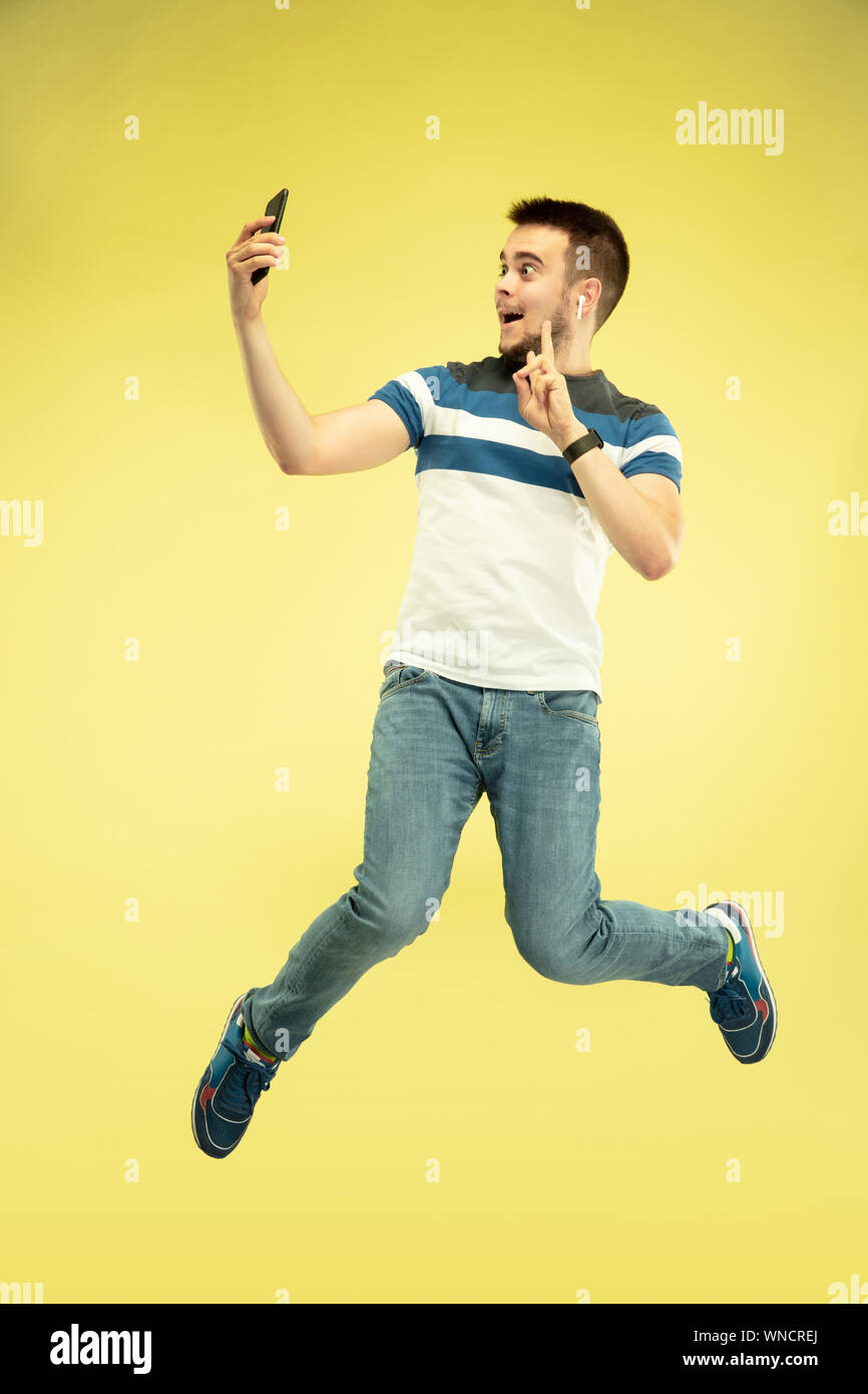 Communication. Full length portrait of happy jumping man with gadgets ...