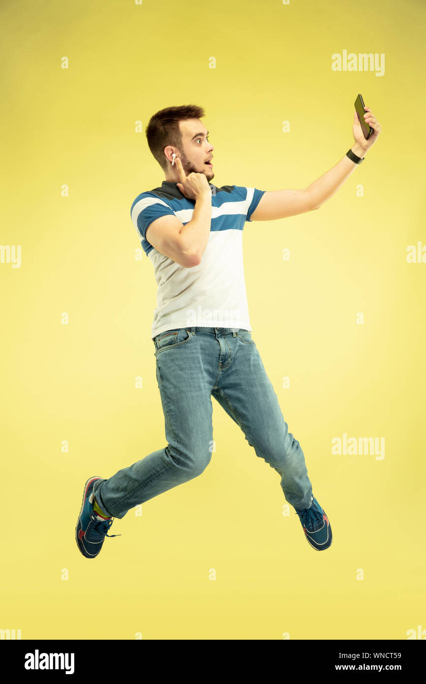Communication. Full length portrait of happy jumping man with gadgets ...