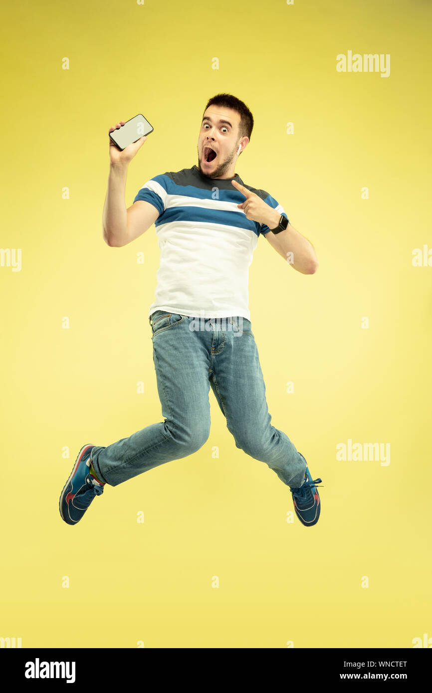 Communication. Full length portrait of happy jumping man with gadgets ...