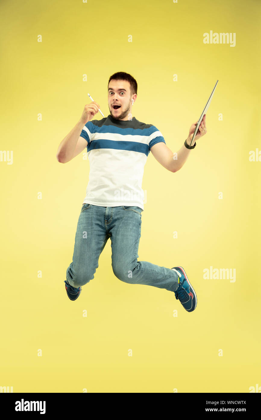 Full length portrait of happy jumping man with gadgets on yellow ...