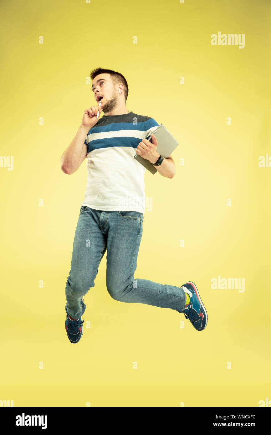 Full length portrait of happy jumping man with gadgets on yellow ...