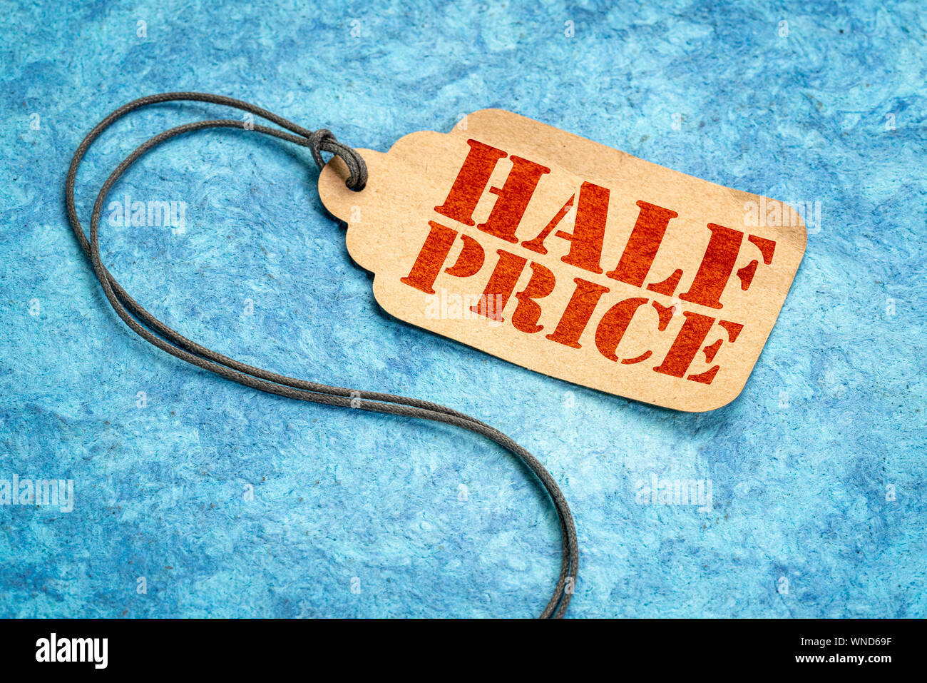 half price sign - a paper price tag with a twine against blue textured ...