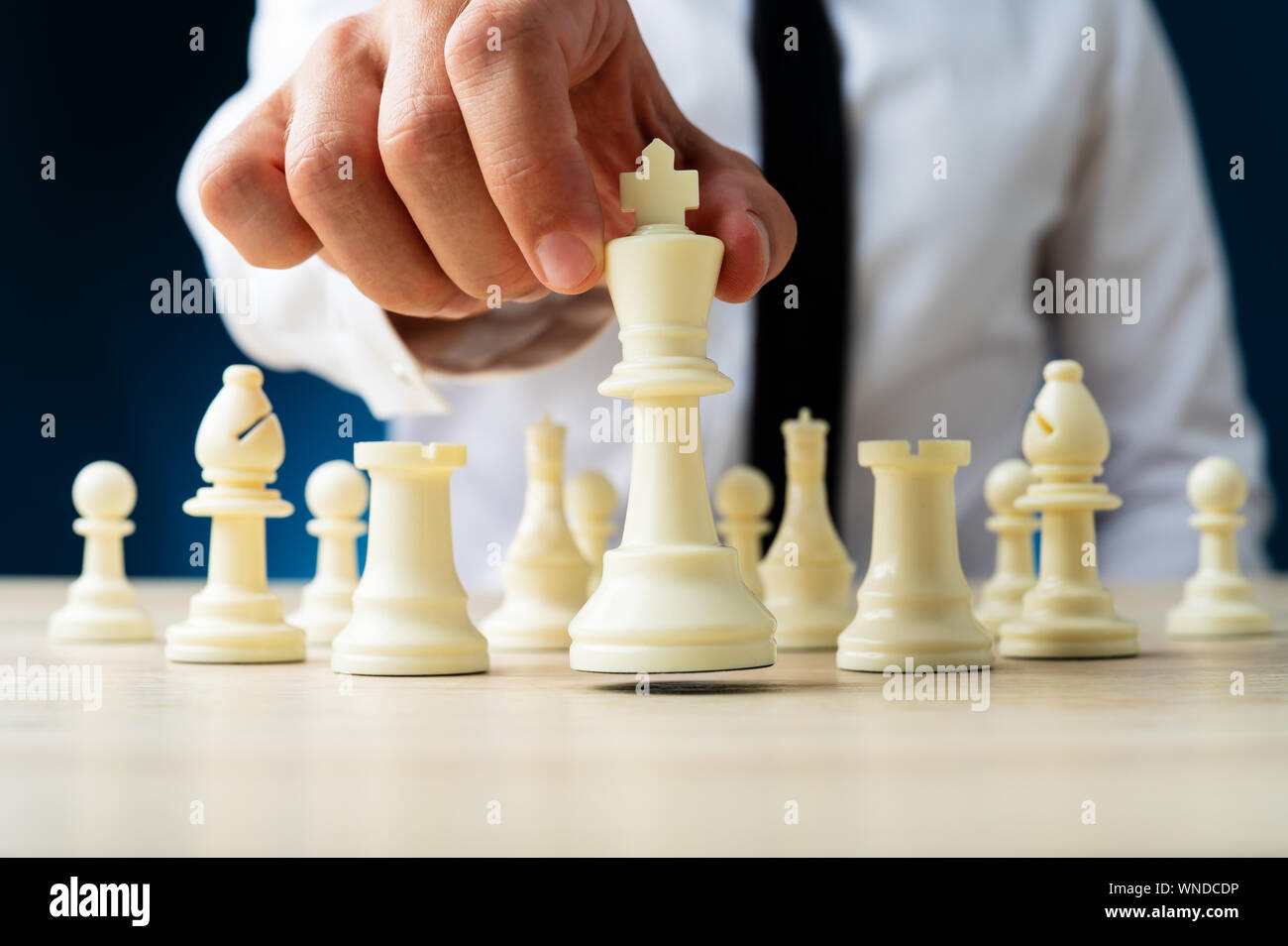 Front view of businessman sitting at his desk positioning white chess ...