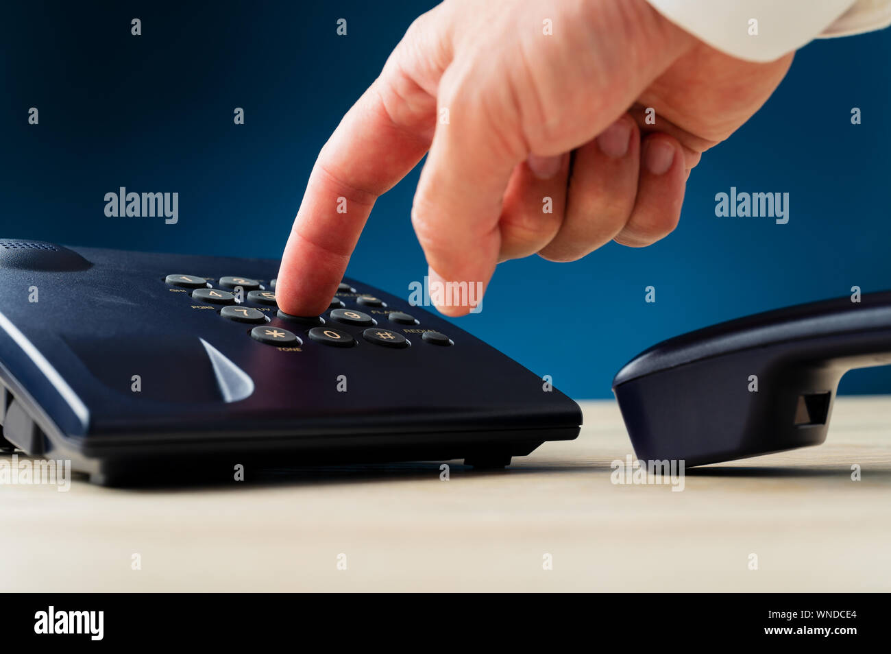 Closeup of male finger pressing a button on landline telephone keypad ...