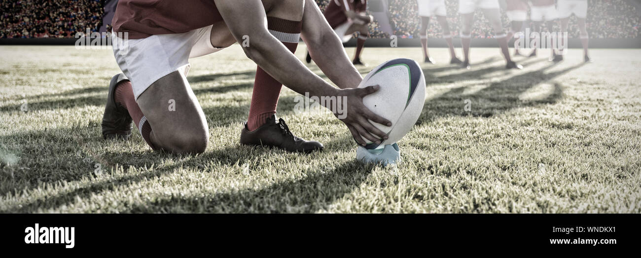 Composite image of male rugby player placing rugby ball on a stand in ...