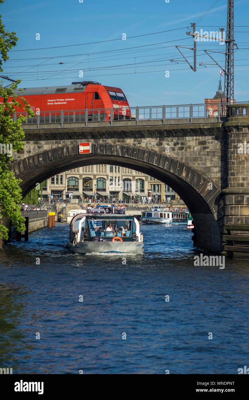 A tour boat sails under a railroad bridge that runs over the Spree ...