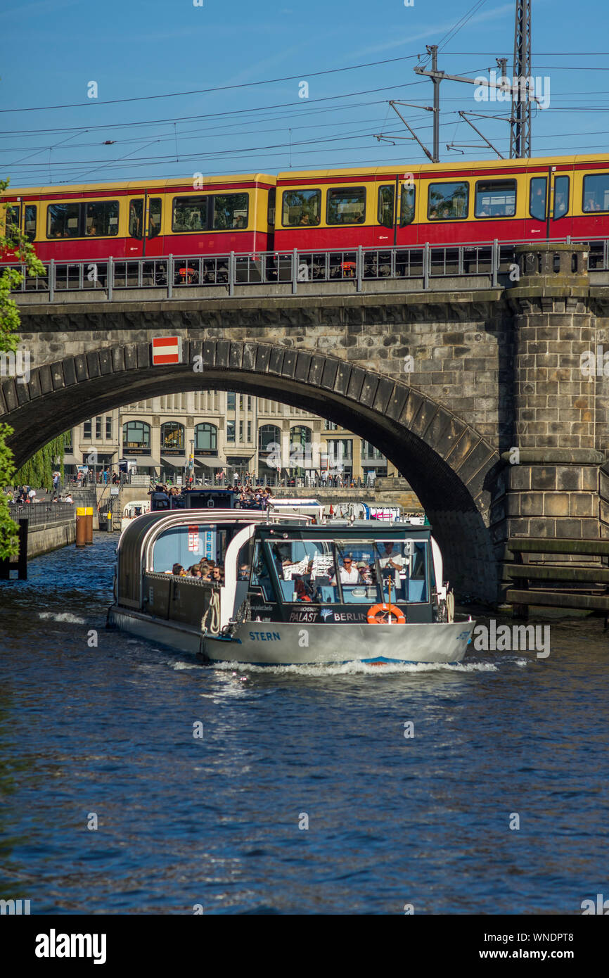 A tour boat sails under a railroad bridge that runs over the Spree ...