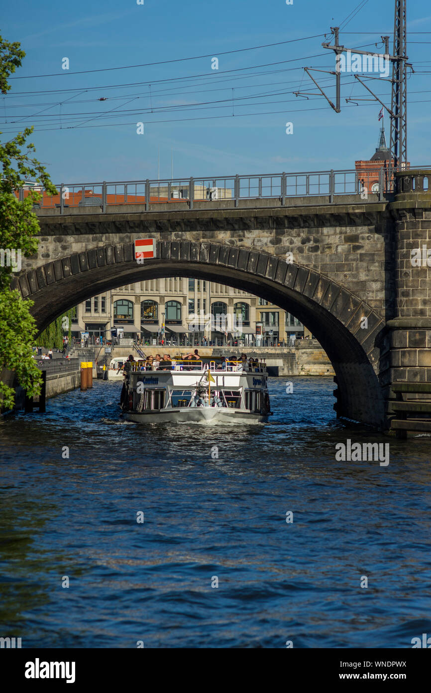 A tour boat sails under a railroad bridge that runs over the Spree ...