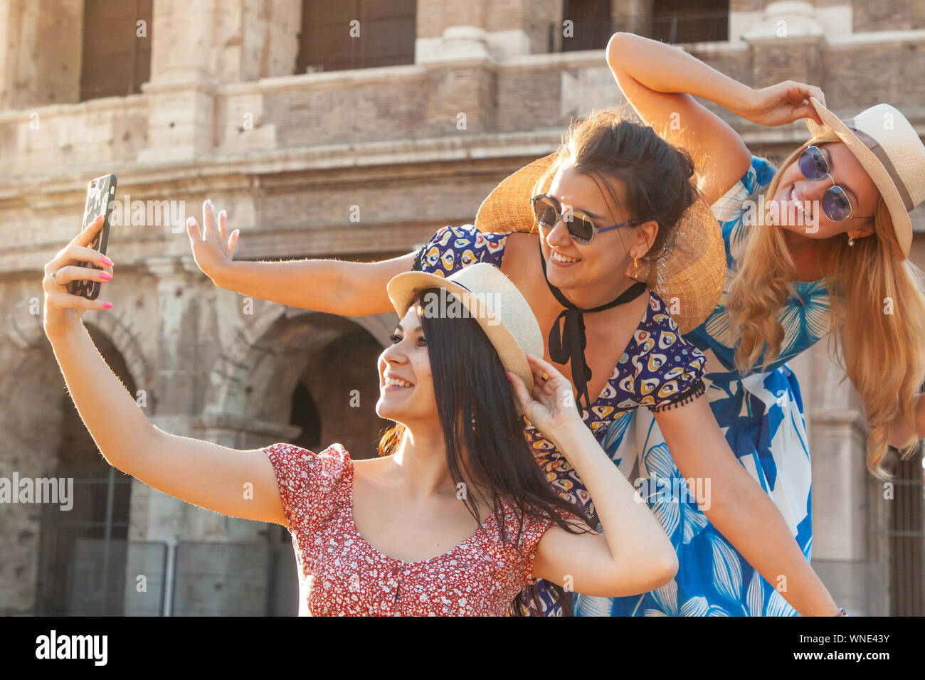 Three happy young women friends tourists taking selfies at Colosseum in ...