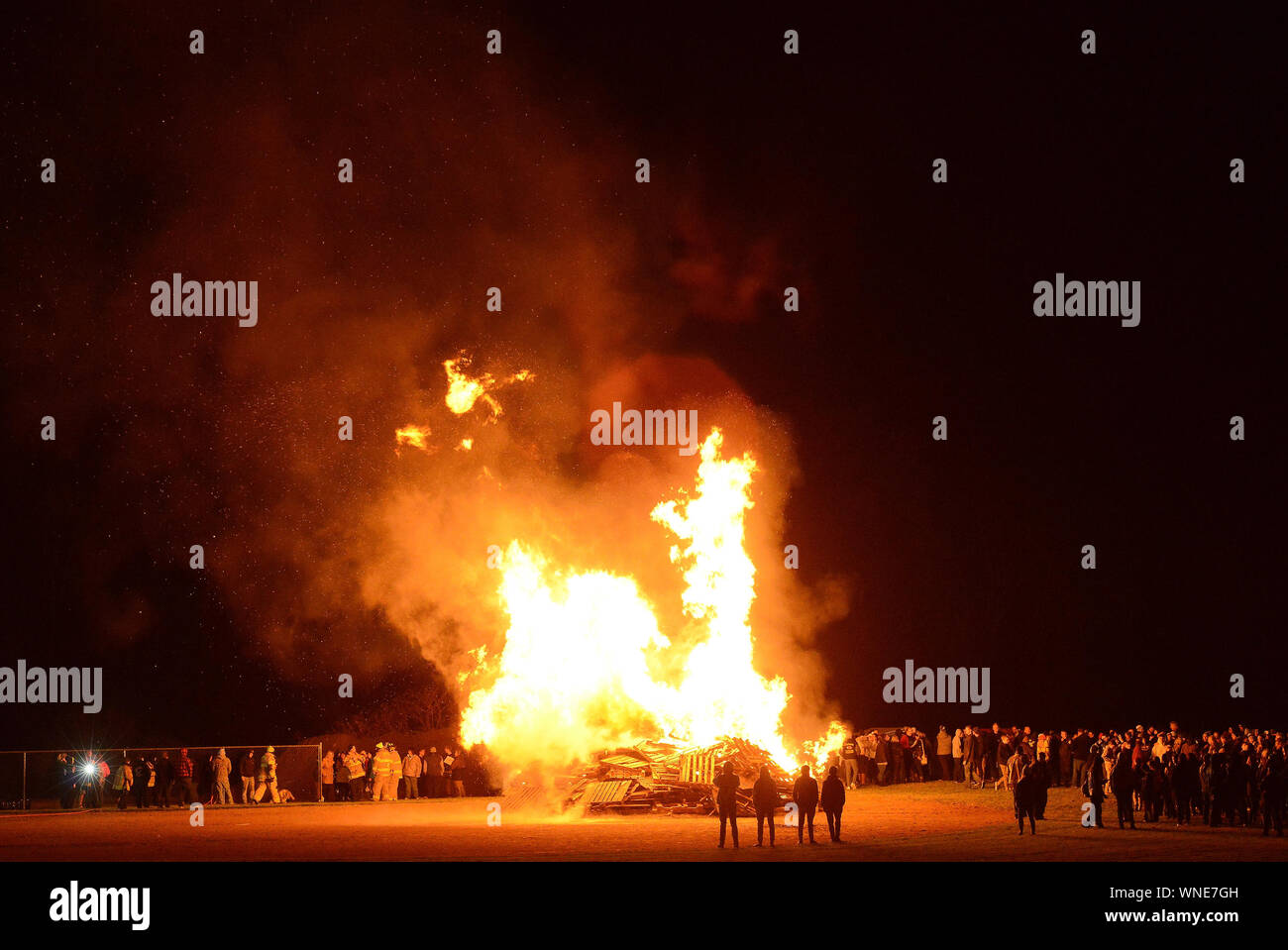 Participants stand around the bonfire during a pep rally to cheer on ...