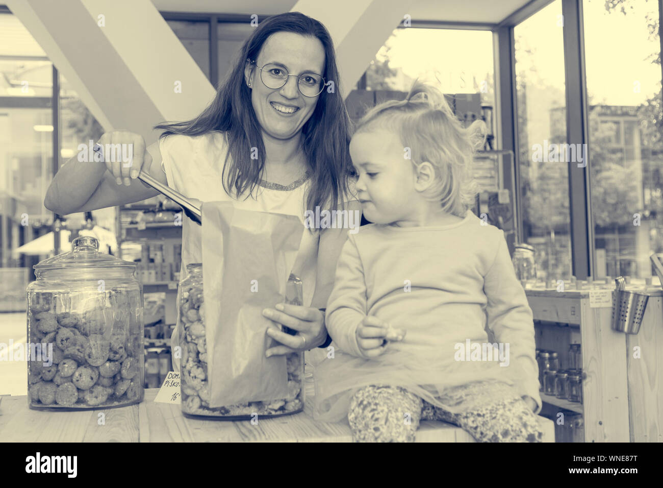 Young mother trying to fill bag with delicious cookies while her mother ...