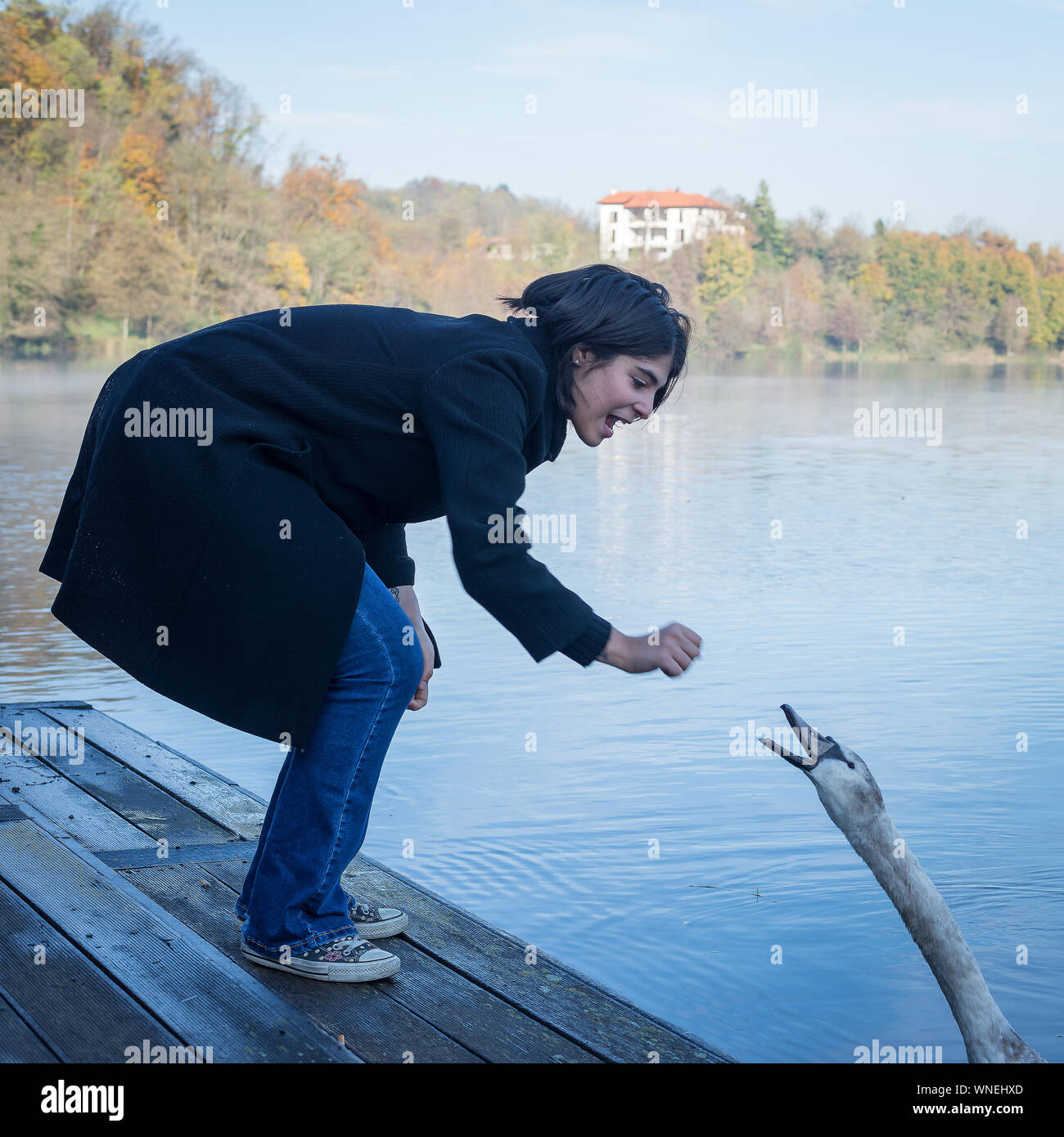 Dark-haired girl wears a black dress and poses outdoors near a white ...