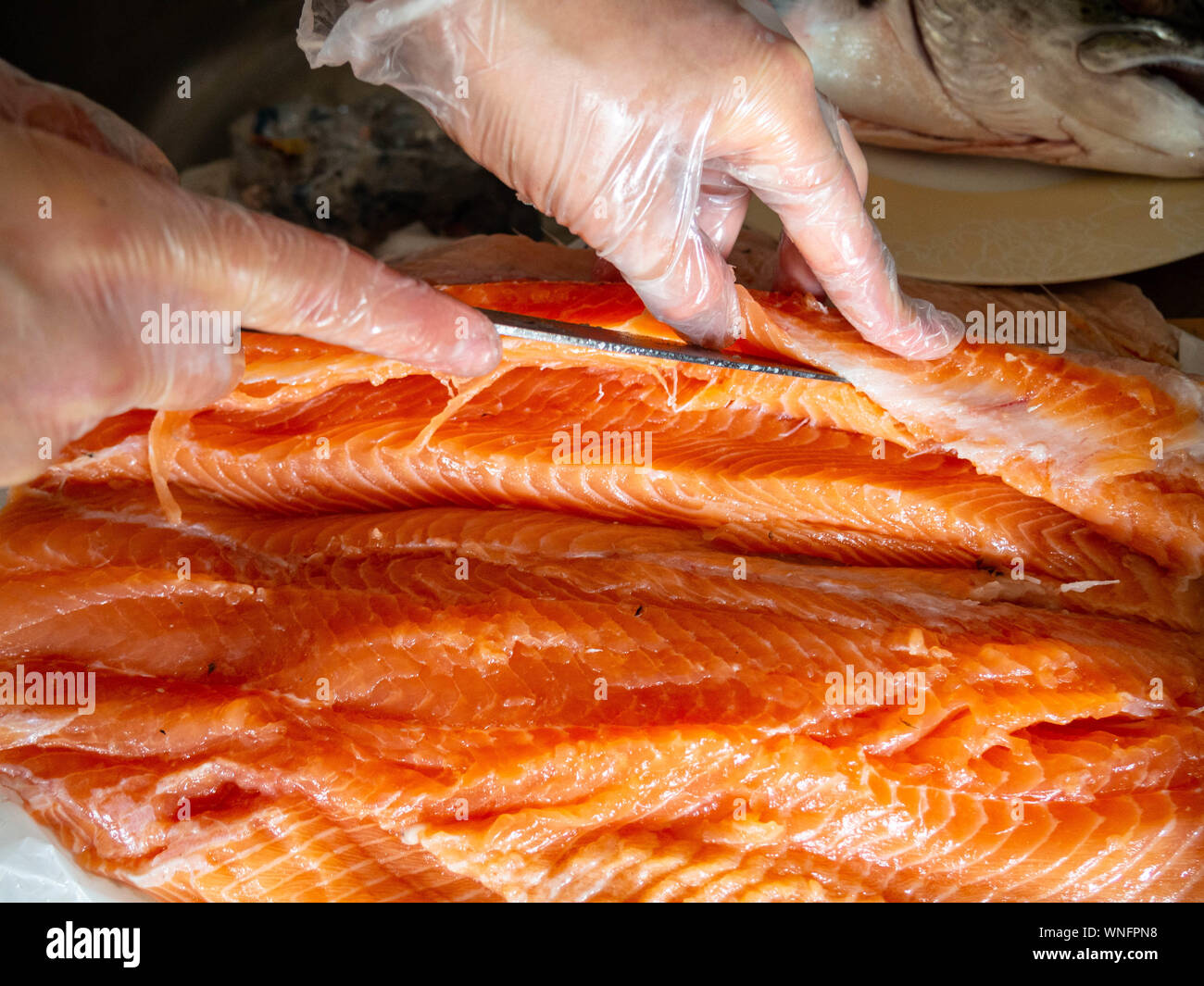 Closeup of worker's hands cutting fish with knife at table Stock Photo ...