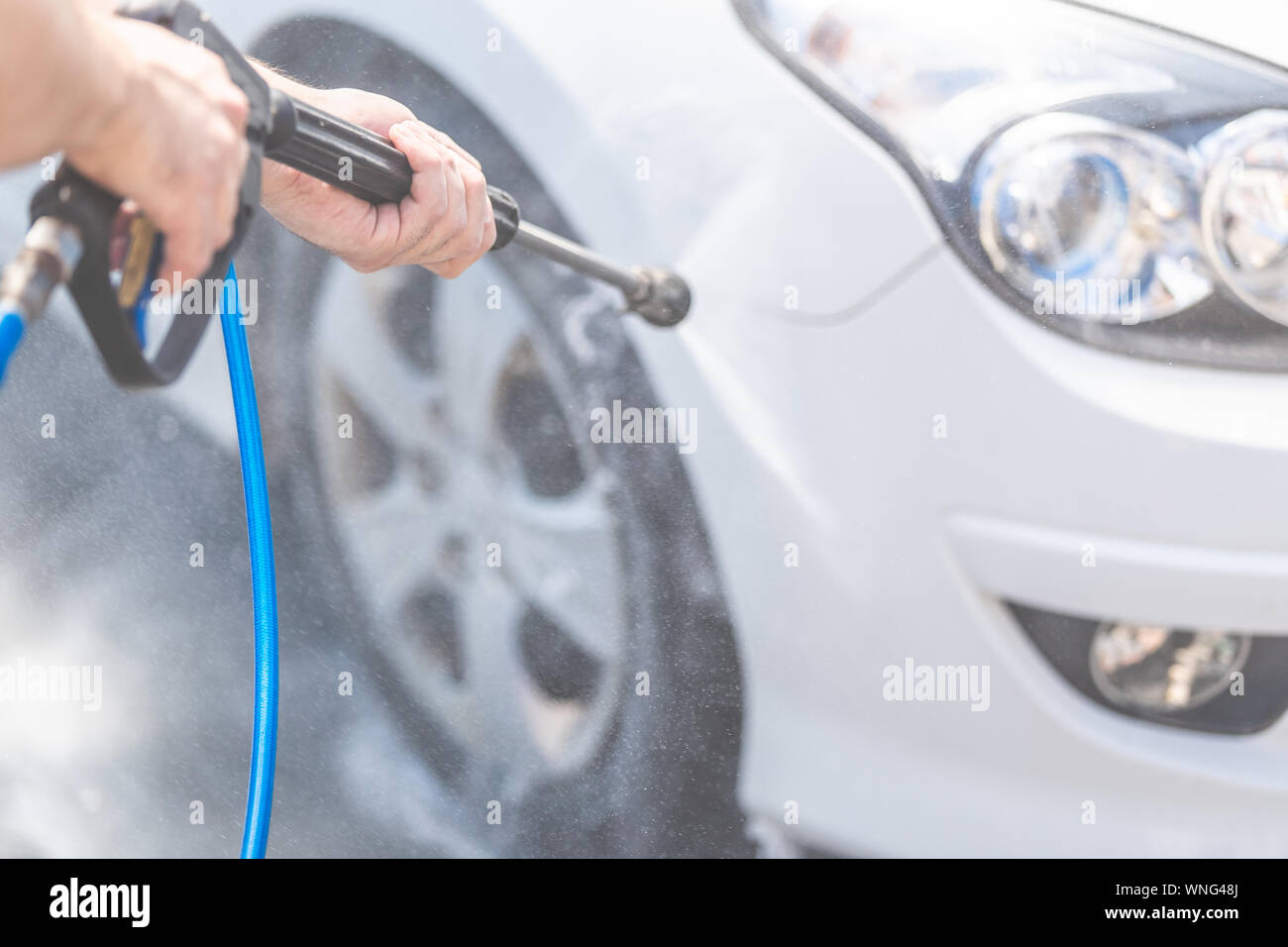 Close up of man washing his car with pressurized water in car wash ...