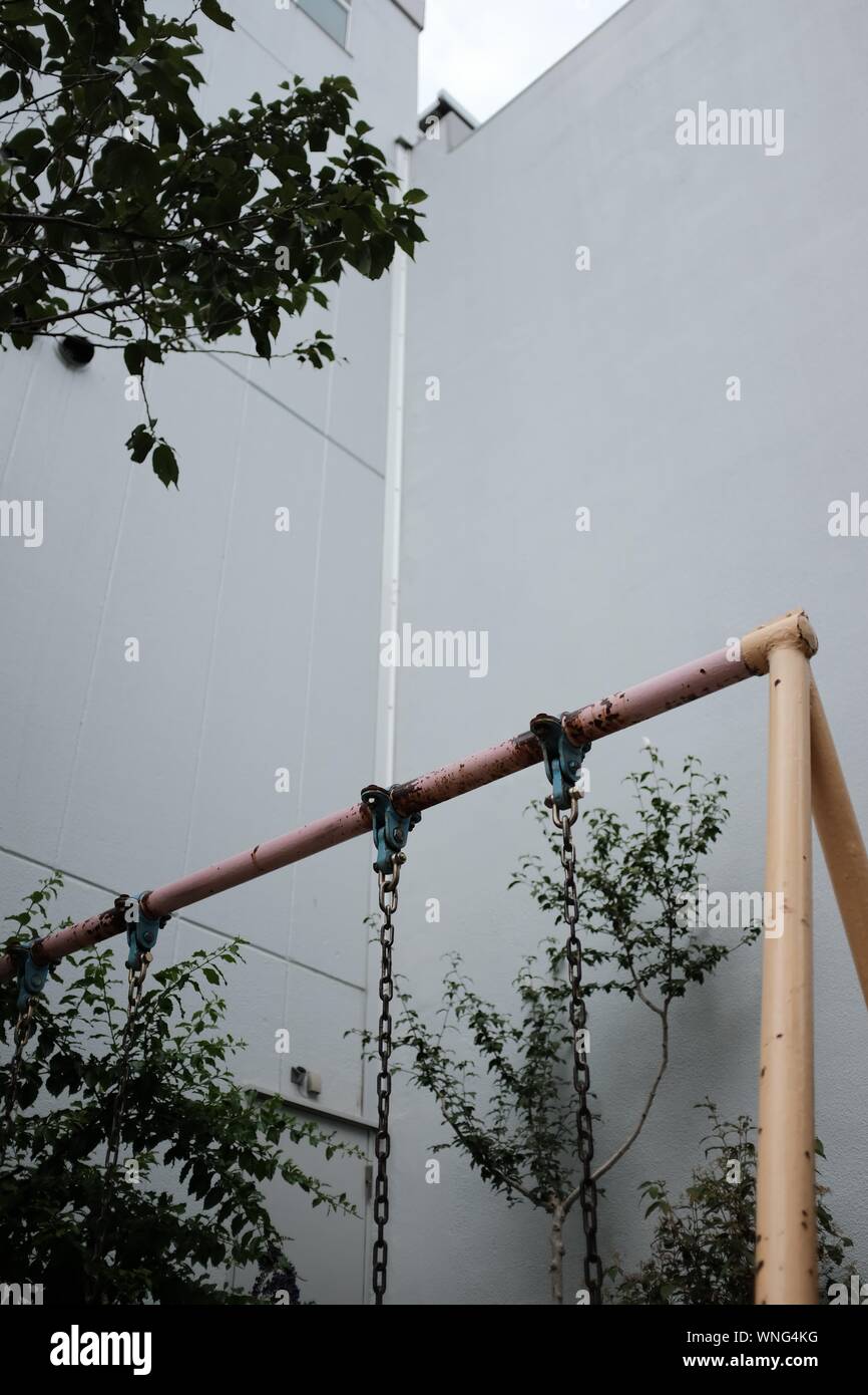 Vertical shot of swing chains hanging from a pole surrounded by green ...