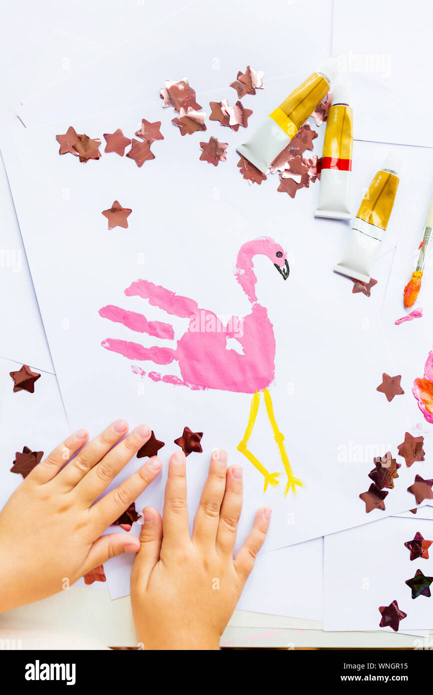 Kid hands and Handprint of pink flamingo. Flat lay, top view, overhead ...