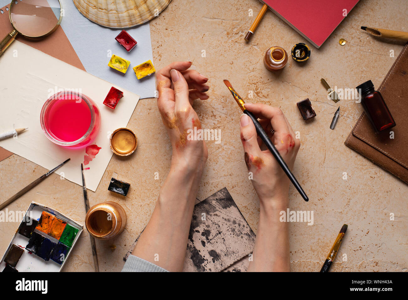 Artist's workspace flatlay with female hands holding a brush. Art ...