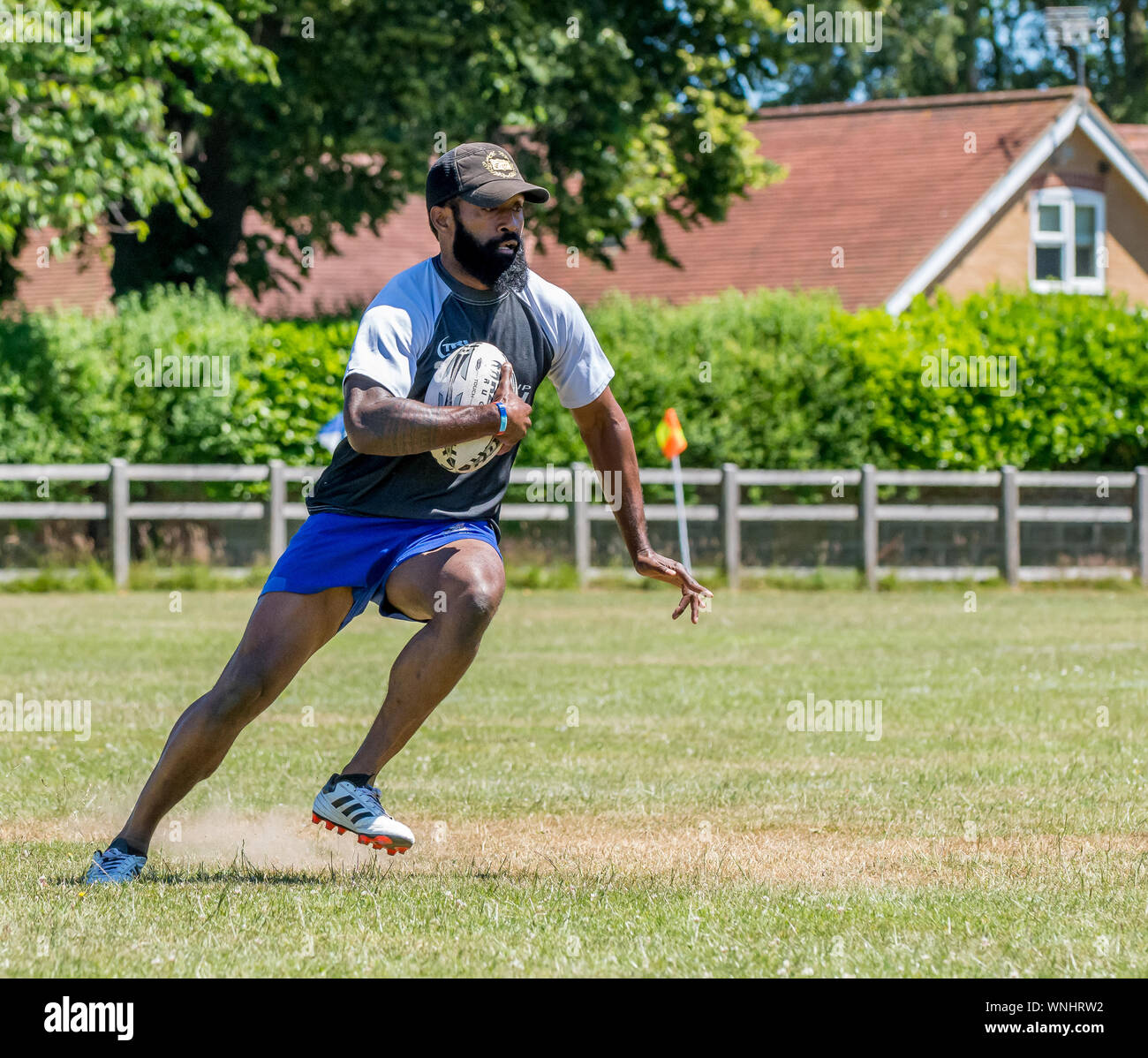 Amateur rugby touch player (male, 40-50 y) runs forwards with rugby ...