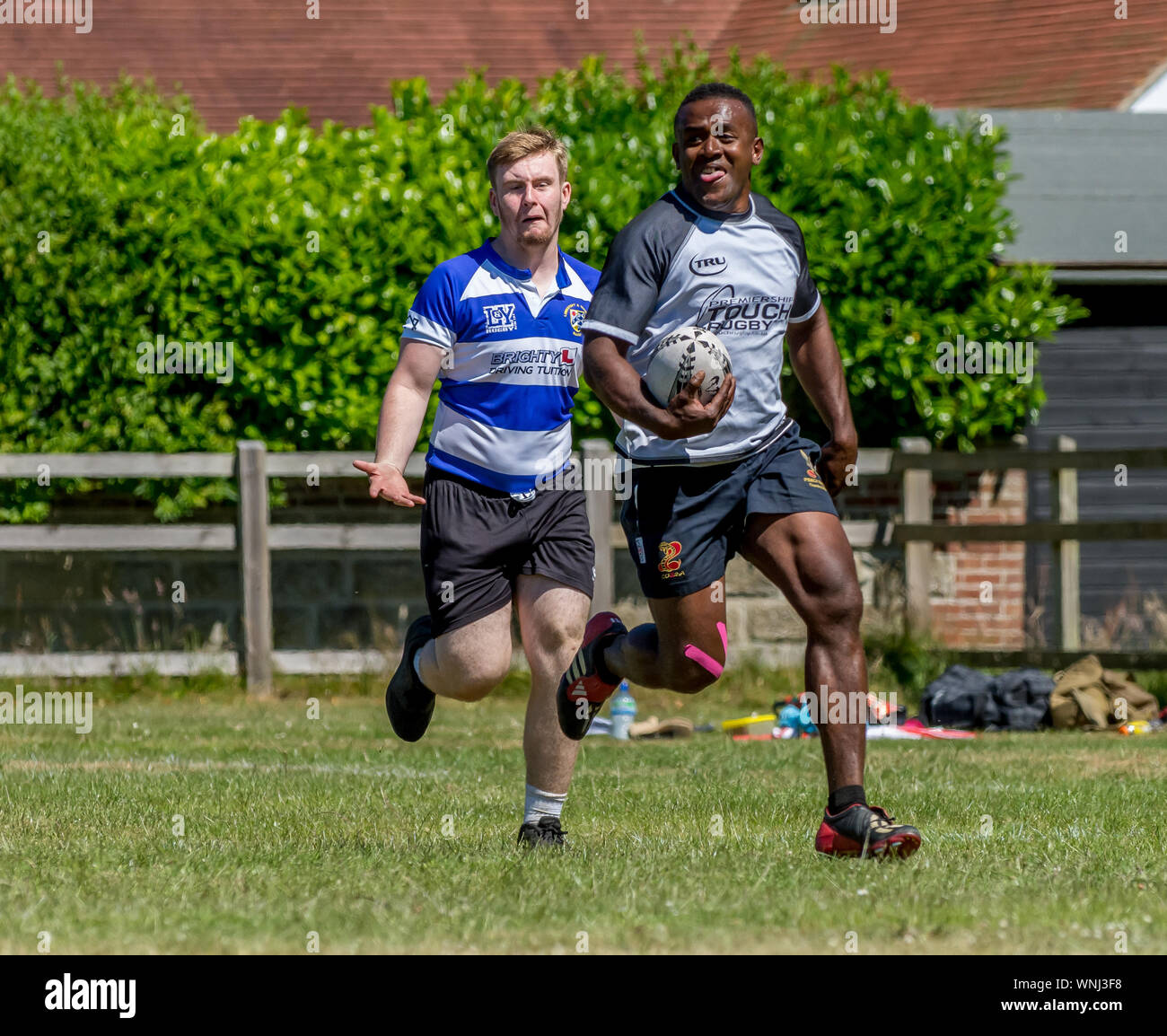 Amateur rugby touch player (male, 40-50 y) sprints forward with ball on ...
