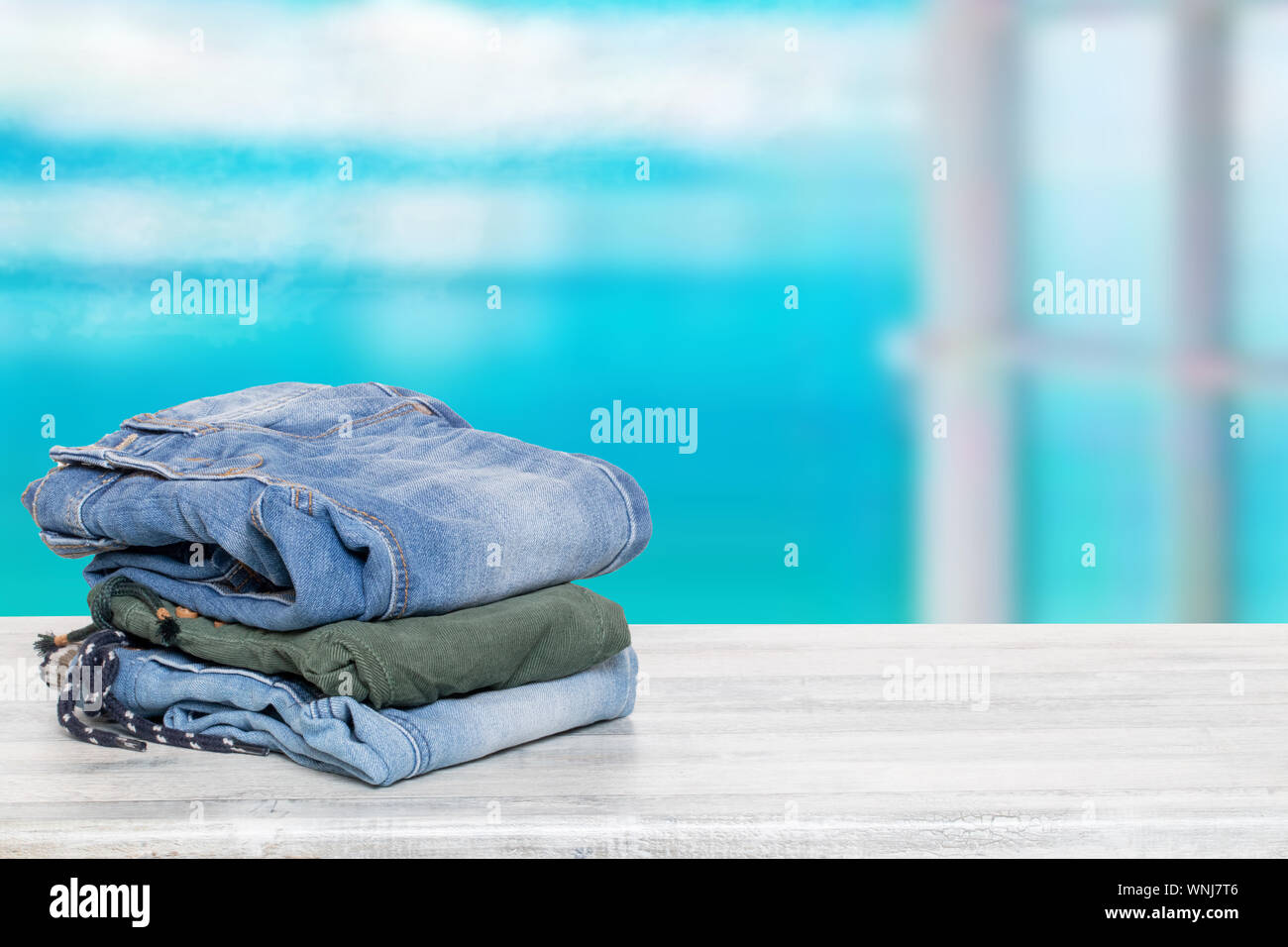 Stack of jeans. Closeup of a pile of colorful denim pants on a bright ...