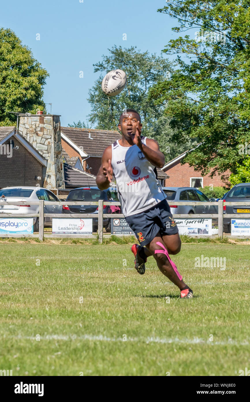 Amateur rugby touch player (male, 40-50 y) reaches forwards to catch ...