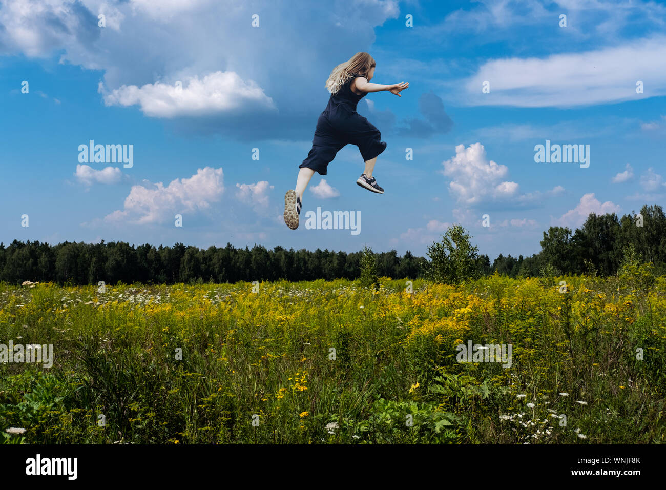 Cute girl jumping funny in clouds above earth. Happy small cheerful ...