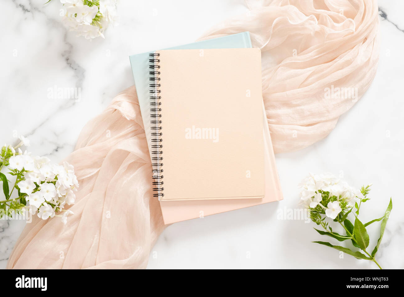 Blank paper notebook, white flowers, pastel blanket on marble ...