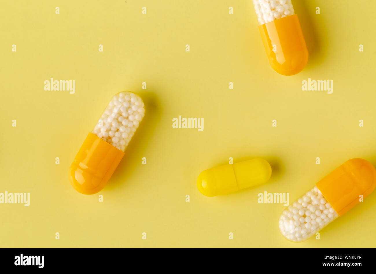 Yellow drug soluble capsules with microgranules inside. Top view. Close ...