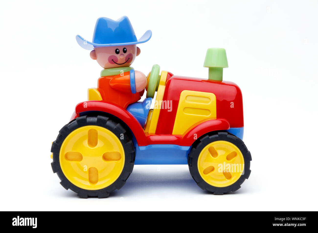Side on shot of a toy tractor and farmer isolated and shot on a white ...