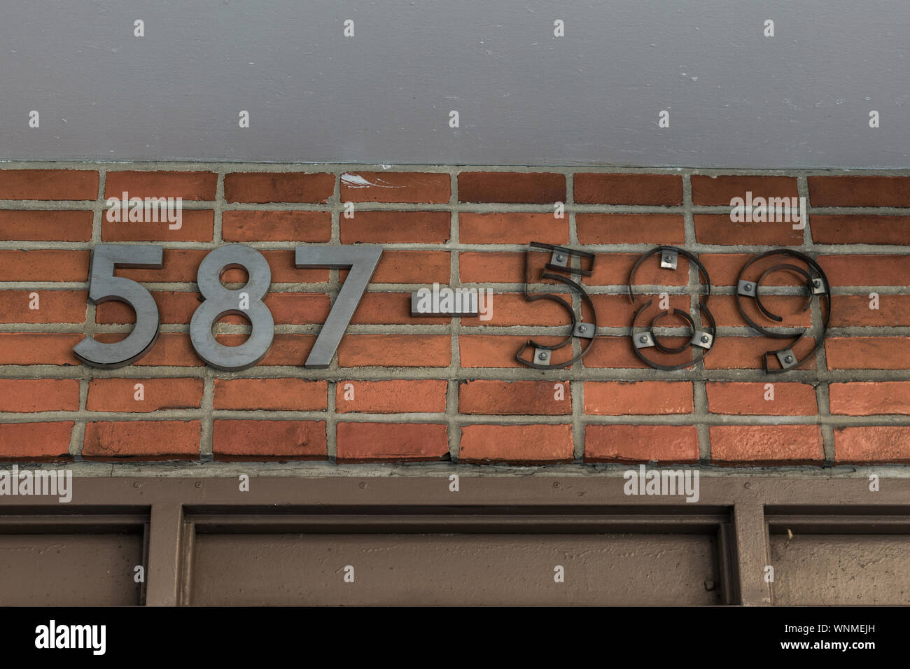 Old building number on a brick wall with some of the numbers missing ...