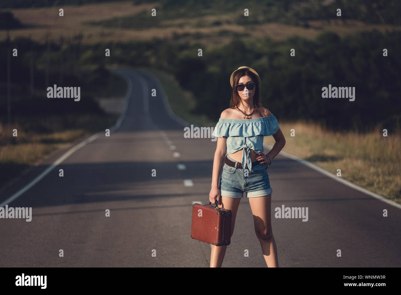 women is hailing a car on a road. Thumbing a ride. Outdoors vacation ...