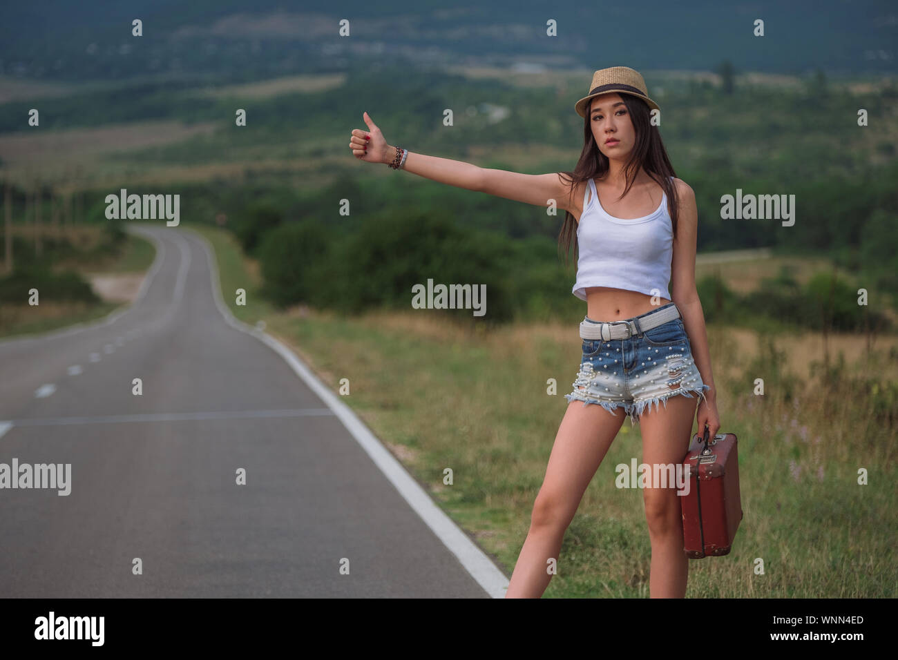 women is hailing a car on a road. Thumbing a ride. Outdoors vacation ...