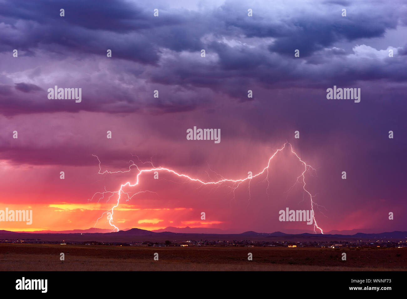 A sunset lightning bolt strikes through dramatic clouds as a ...
