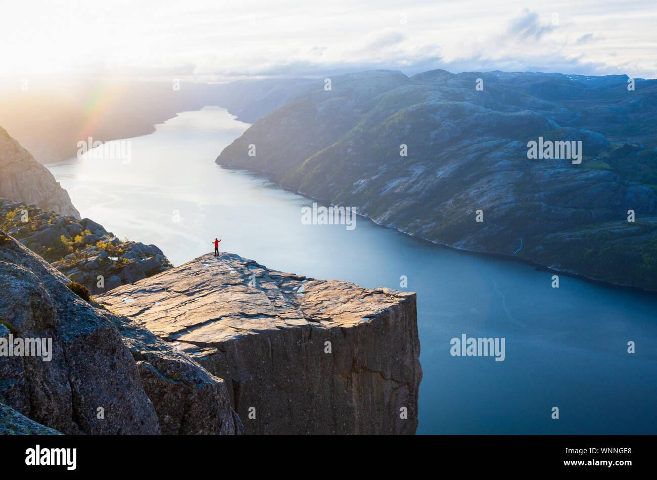 Hiker in bright clothing standing at the edge of Pulpit Rock in Norway ... Hiker in bright clothing standing at the edge of Pulpit Rock in Norway ...