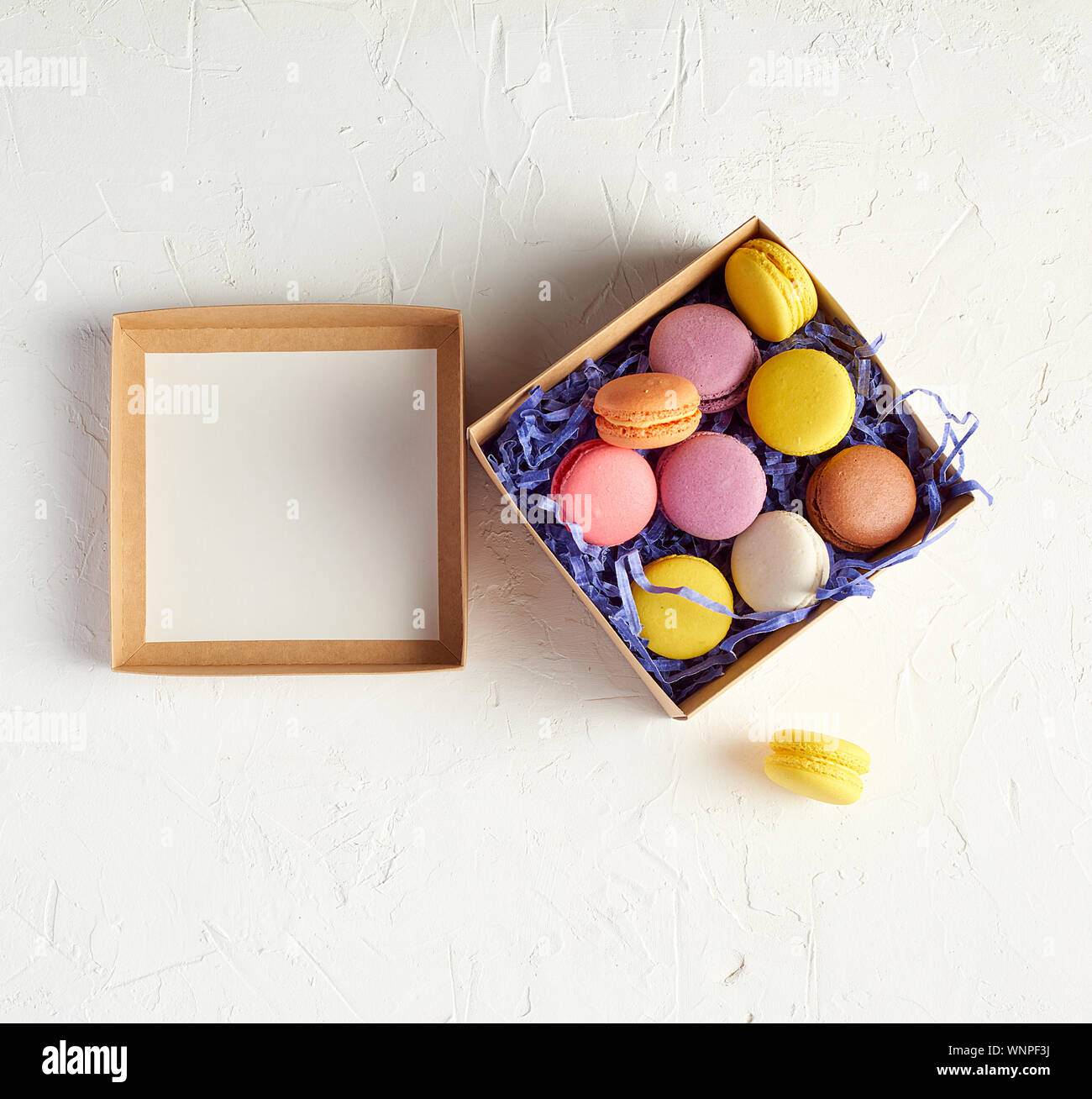 open cardboard box with a baked dessert multi-colored round macarons ...