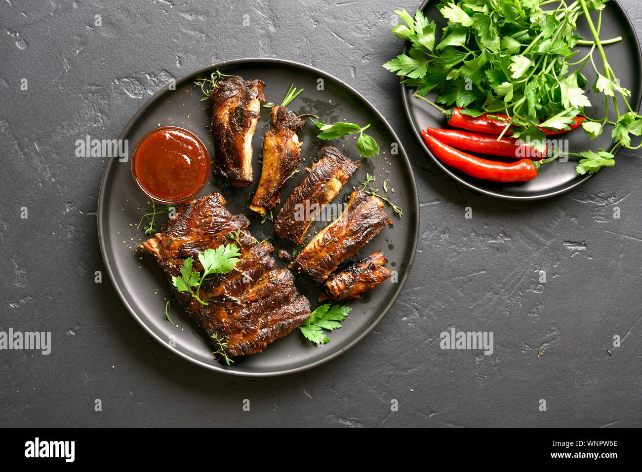 Spicy hot grilled spare ribs on plate over black stone background ...