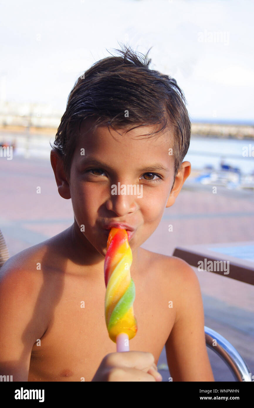 Boy eating a colorful ice cream in the promenade Stock Photo - Alamy