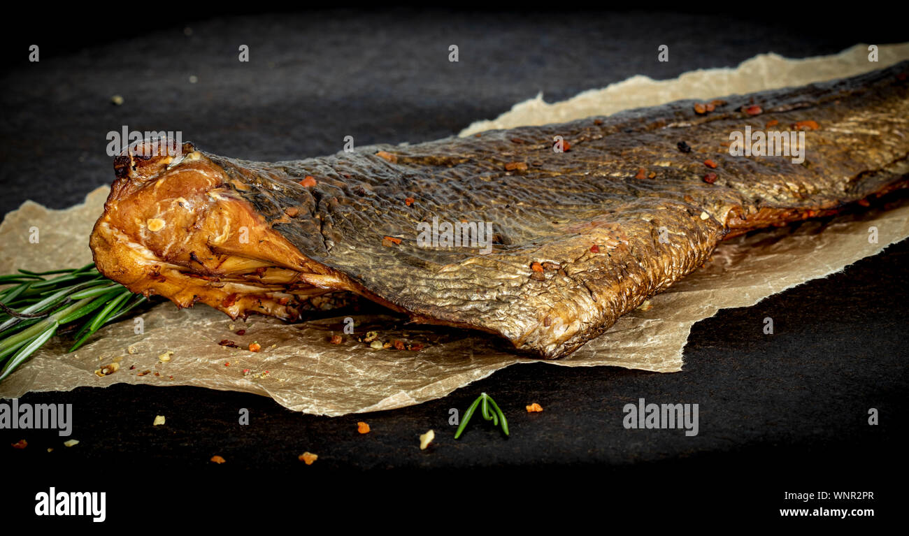 Smoked sea fish on a dark background close-up with sprigs of rosemary ...