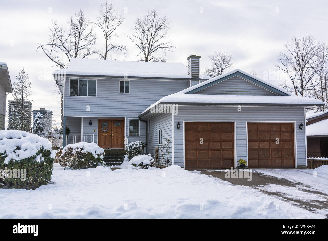 Family house with front yard and driveway in snow on winter cloudy day ...