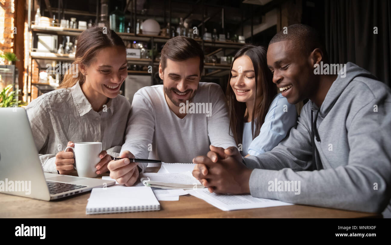 Diverse friends analyzing documents together, doing homework in cafe ...