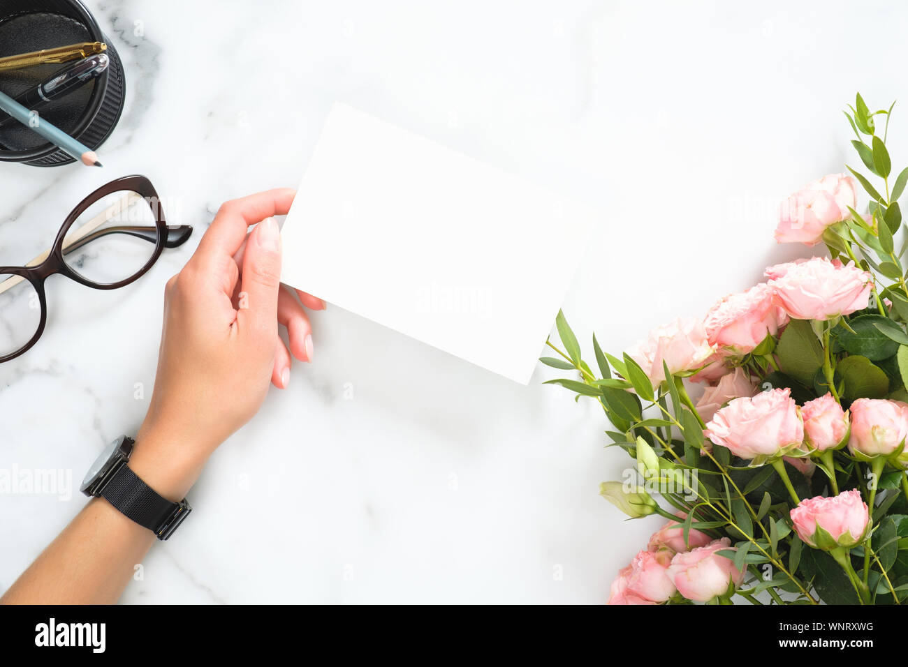 Woman hand holding blank paper card mockup over modern home office desk ...