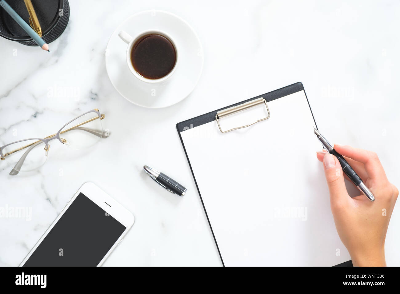 Woman hand write a message in blank clipboard over modern home office ...