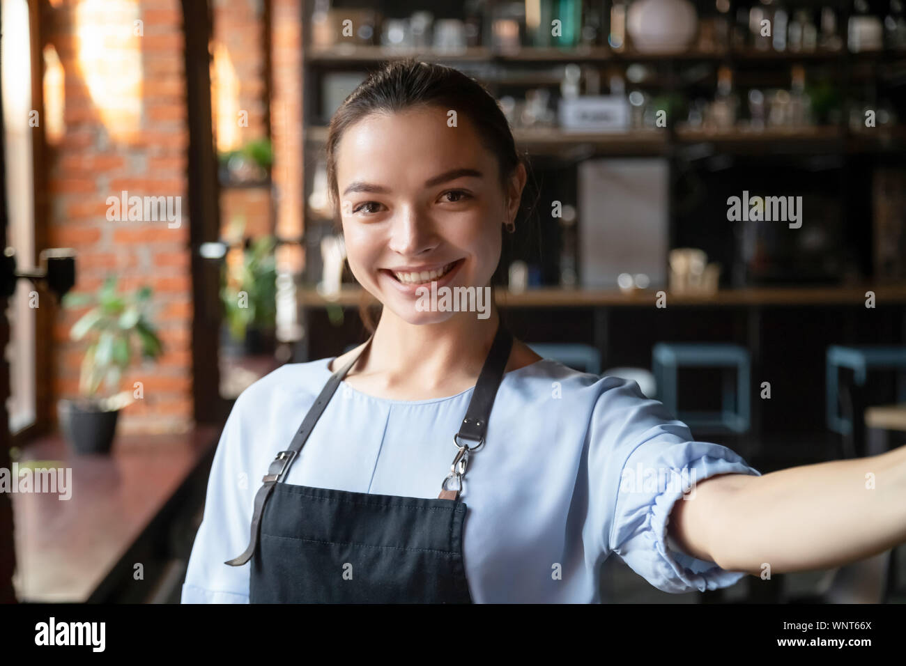 Head shot portrait of attractive smiling waitress in cozy coffeehouse ...